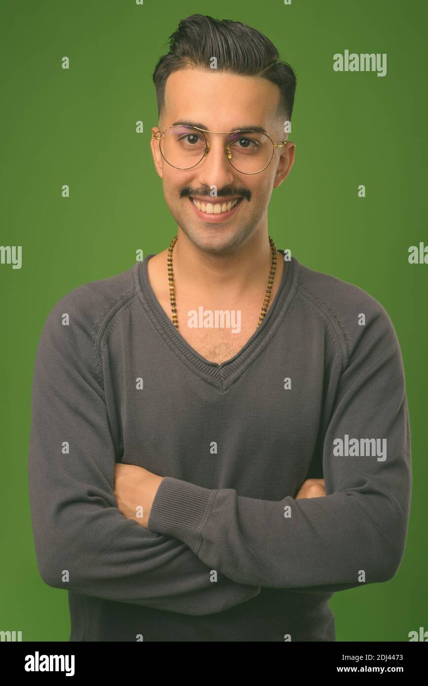 Young handsome Iranian man with mustache against green background Stock ...
