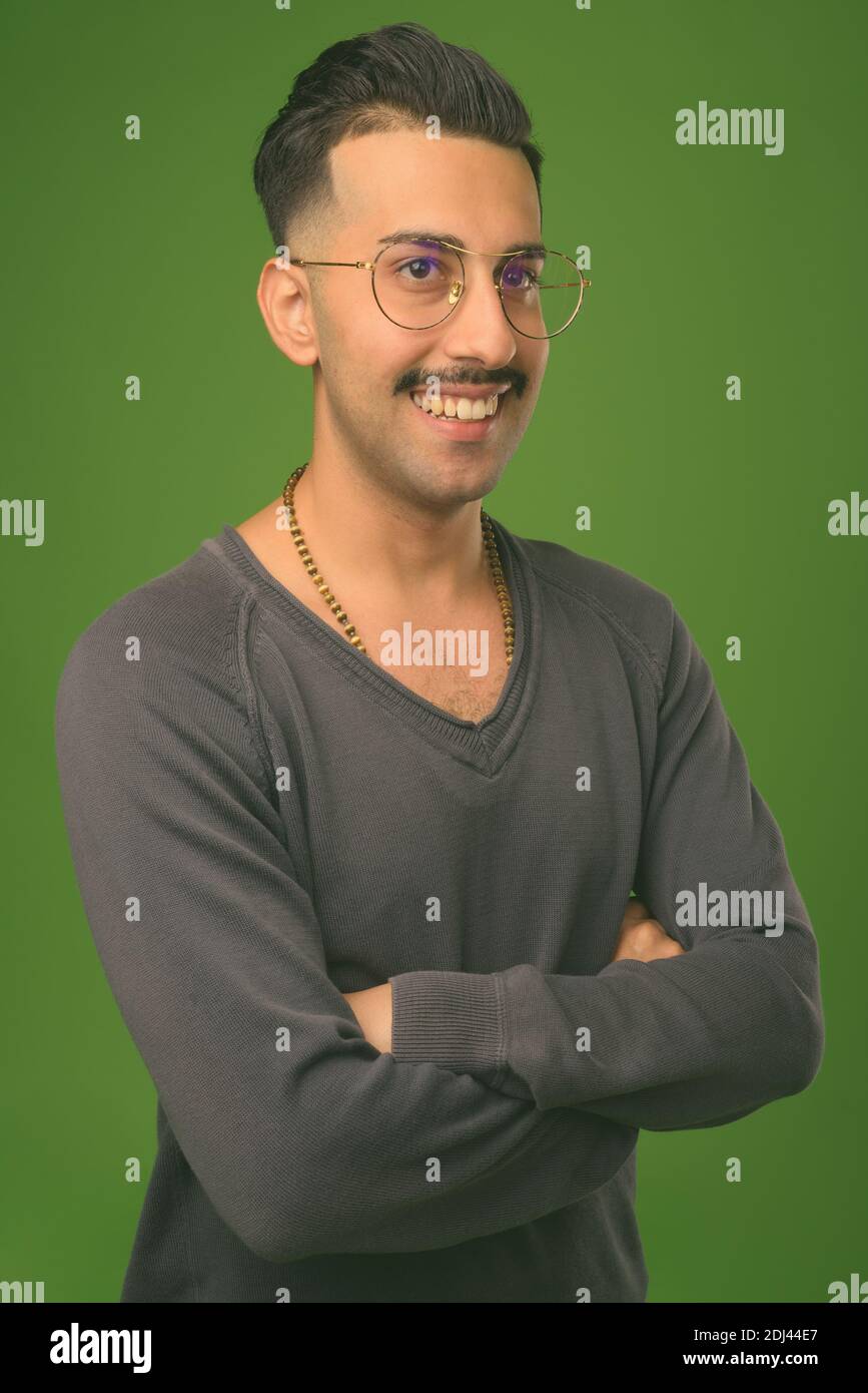 Young handsome Iranian man with mustache against green background Stock ...