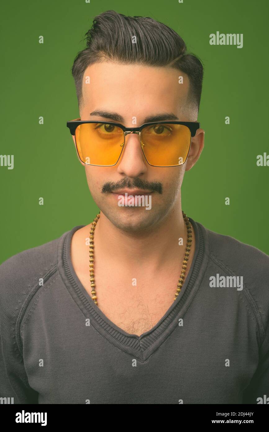 Young handsome Iranian man with mustache against green background Stock ...
