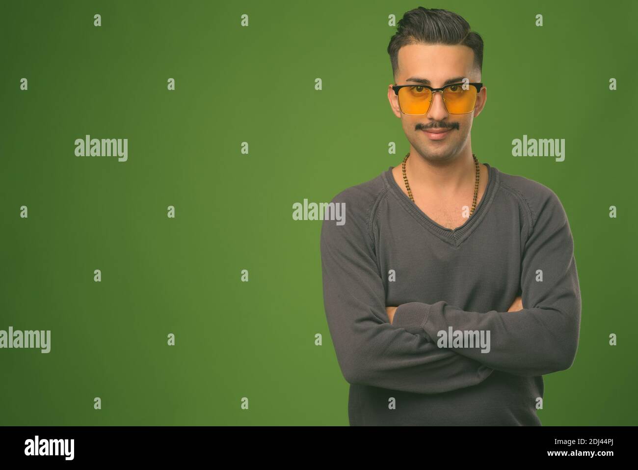 Young handsome Iranian man with mustache against green background Stock ...