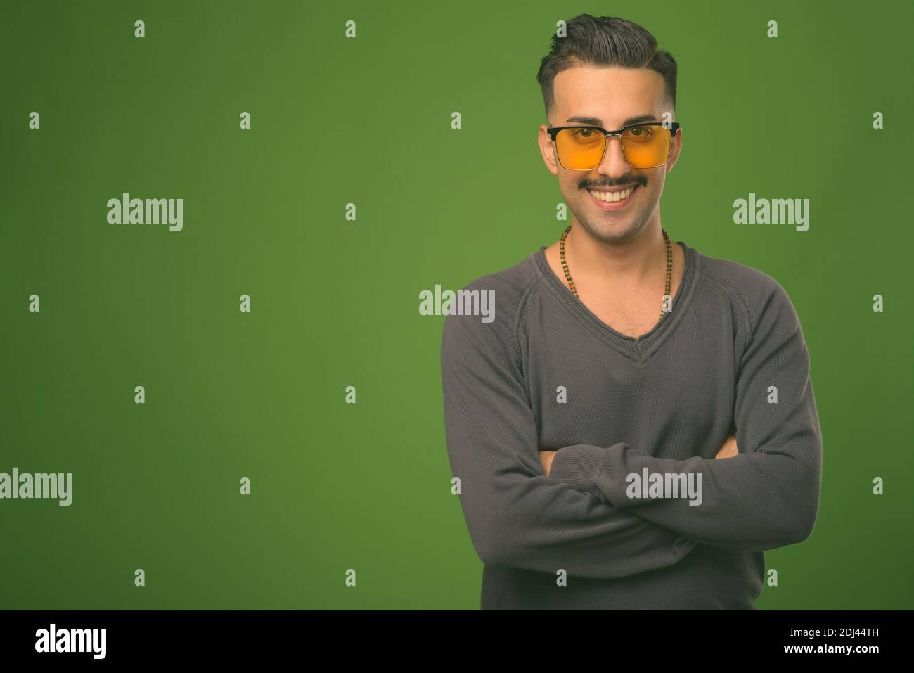 Young handsome Iranian man with mustache against green background Stock ...