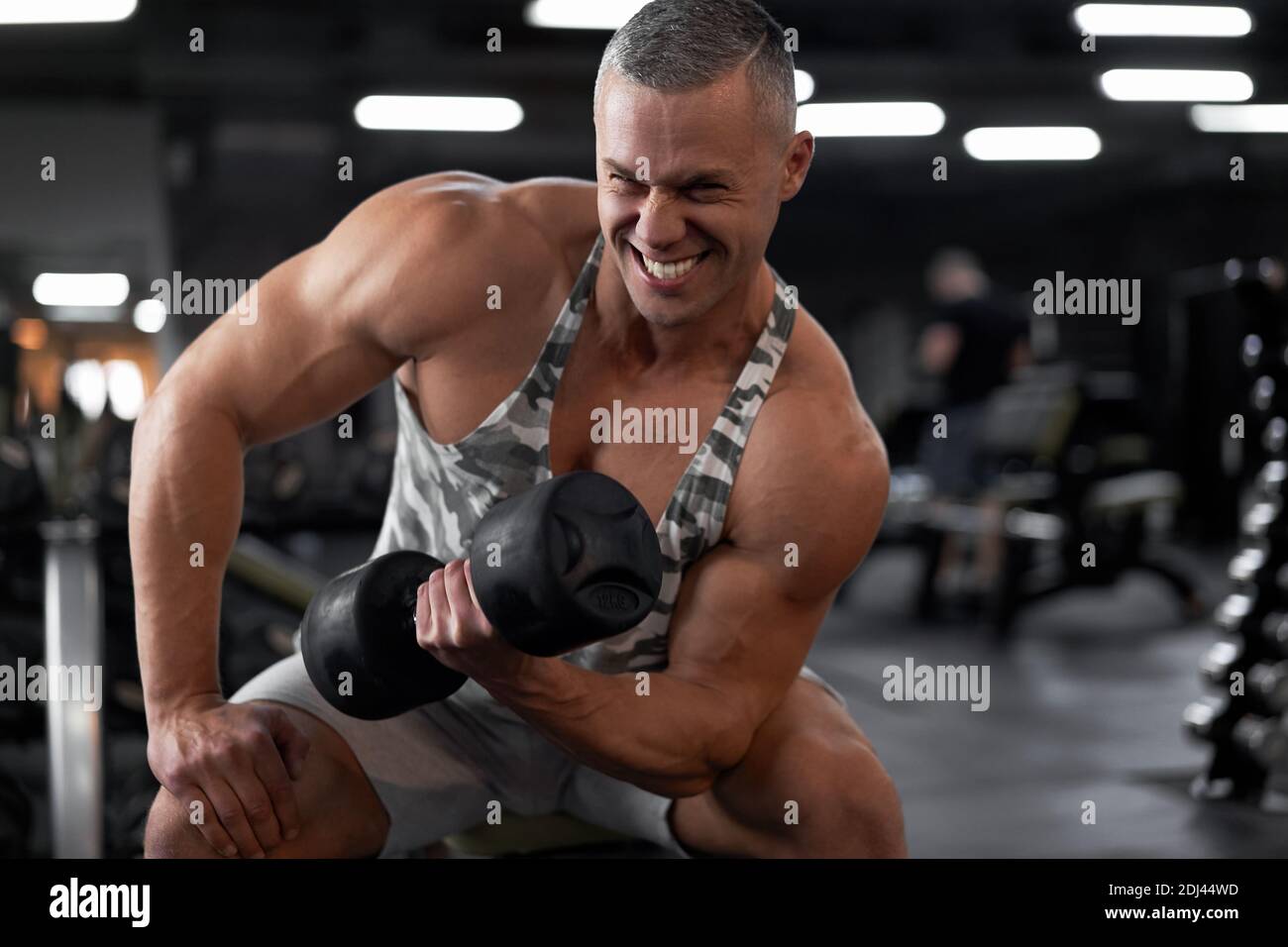 Muscular athletic bodybuilder fitness model sitting bench training ...