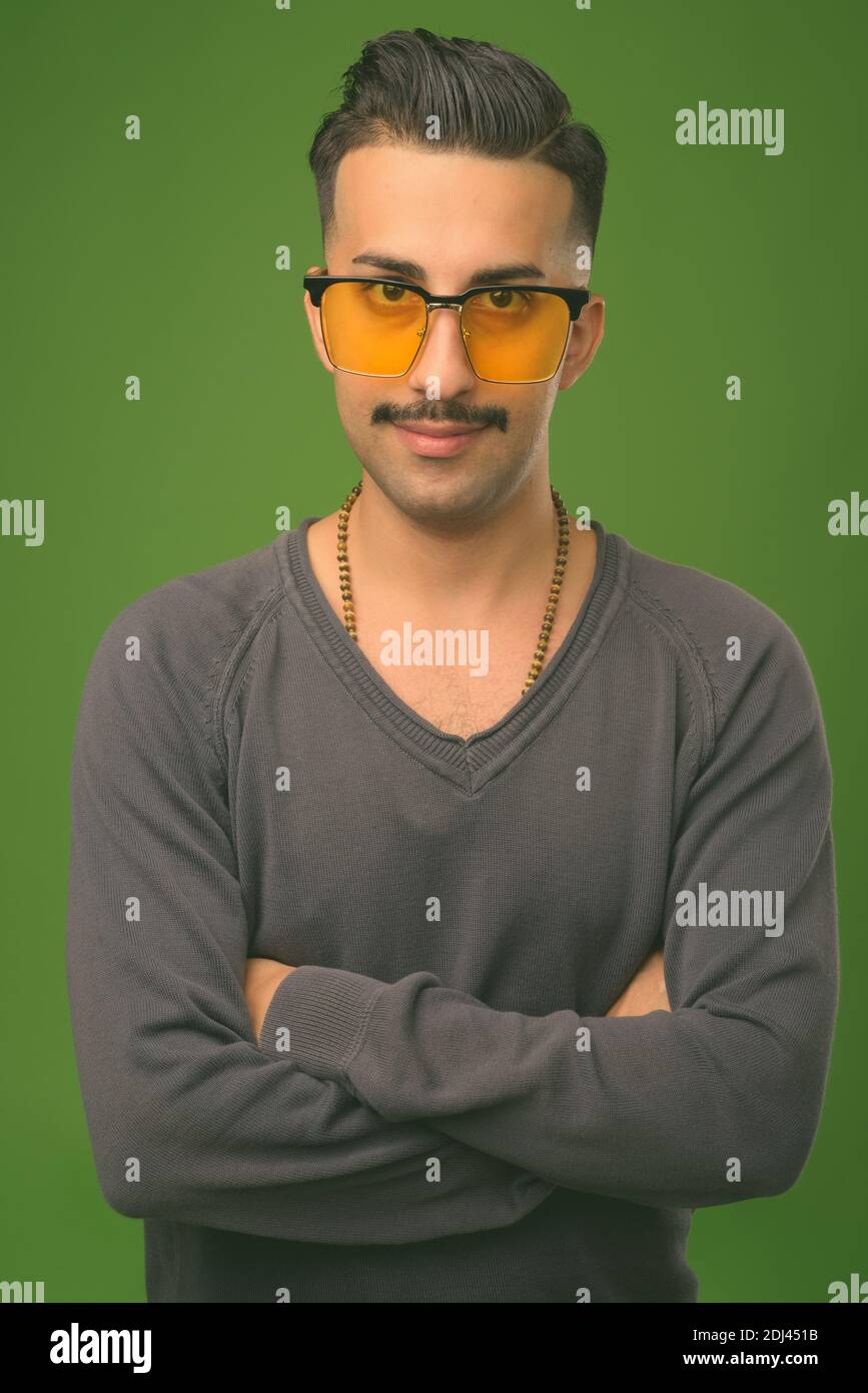Young handsome Iranian man with mustache against green background Stock ...