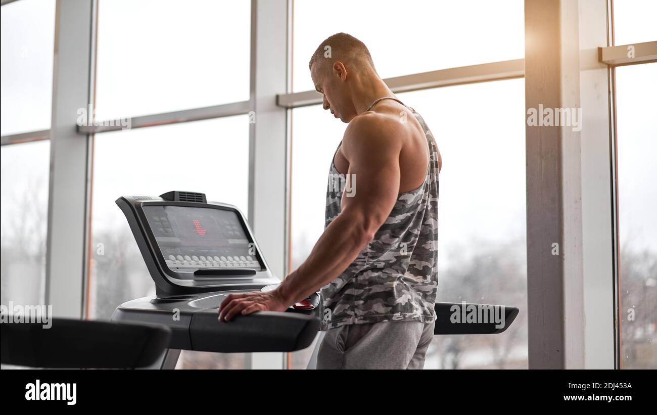 Muscular athletic bodybuilder fitness model running treadmill gym near ...