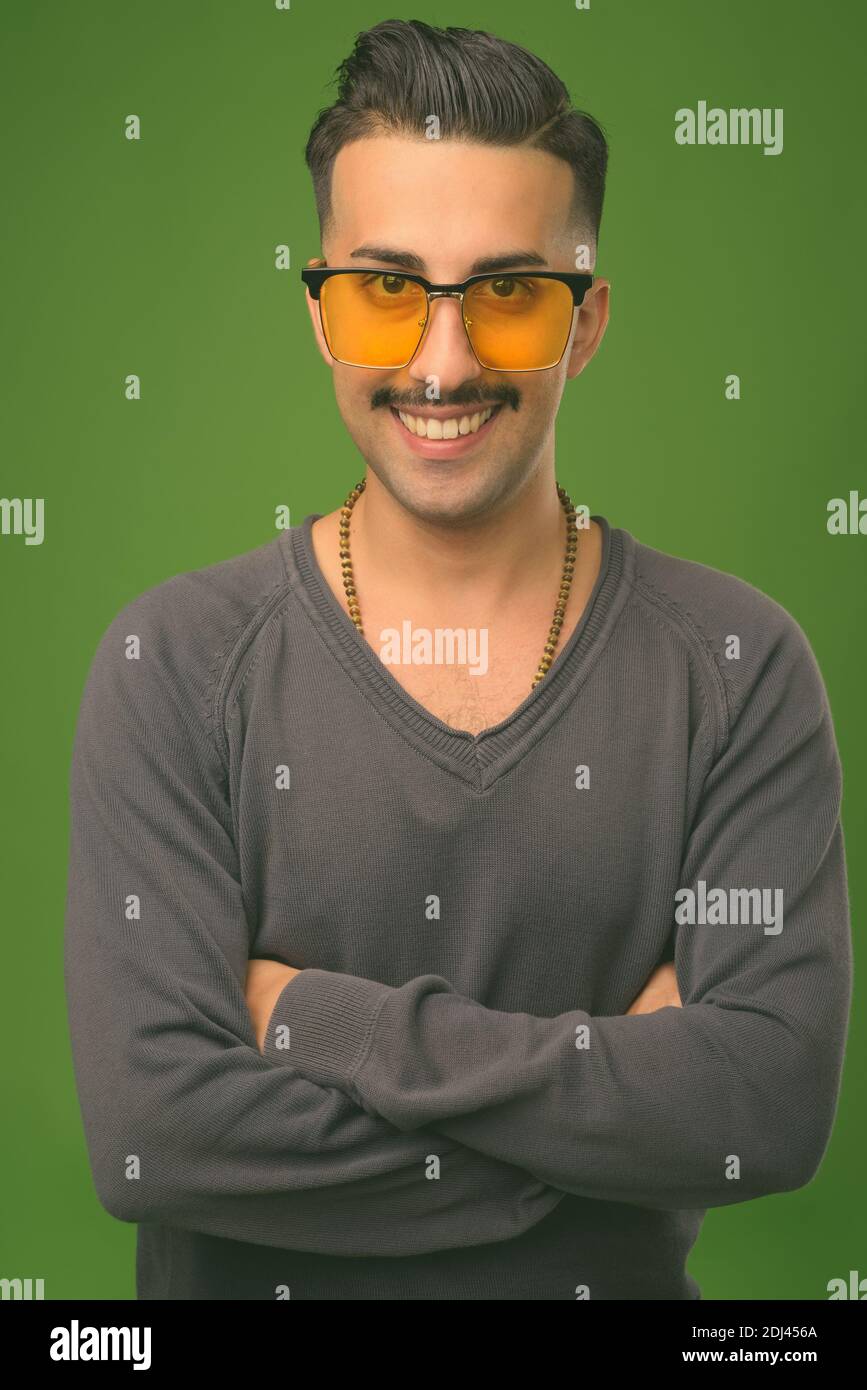 Young handsome Iranian man with mustache against green background Stock ...