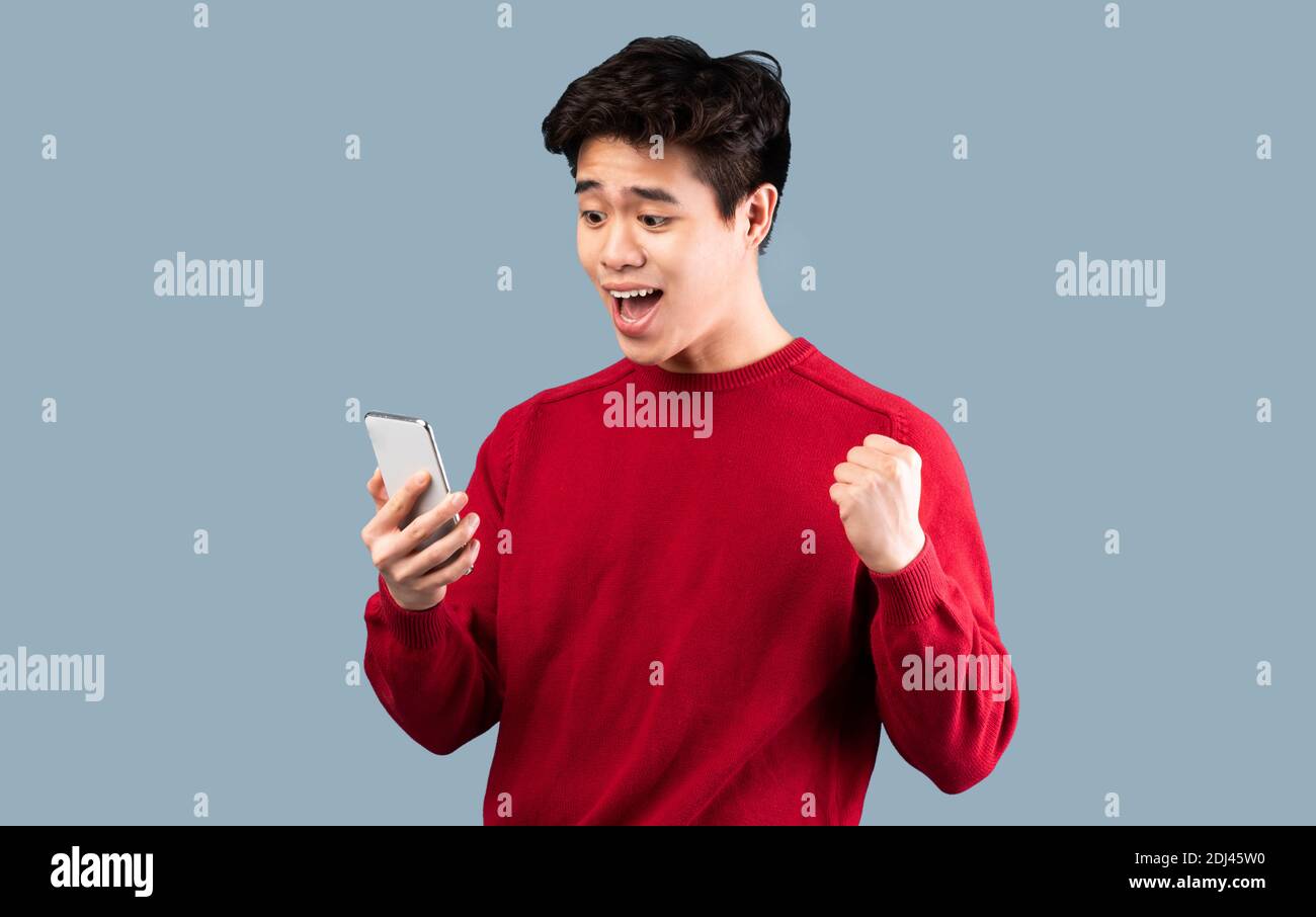 Excited asian man using mobile phone, celebrating online win Stock ...