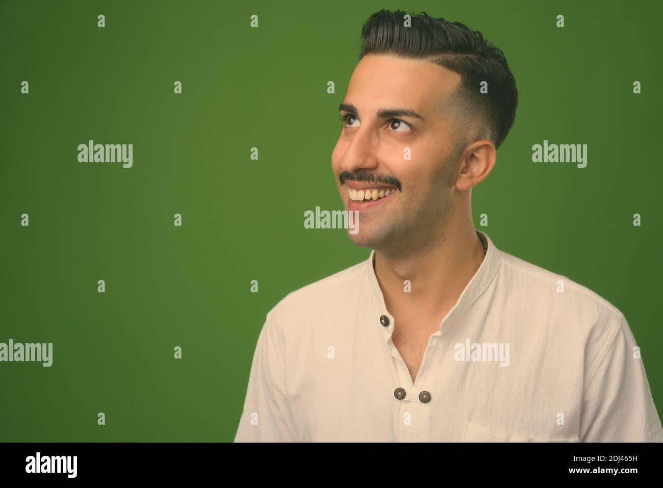 Young handsome Iranian man with mustache against green background Stock ...