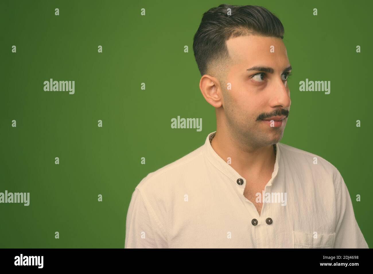 Young handsome Iranian man with mustache against green background Stock ...