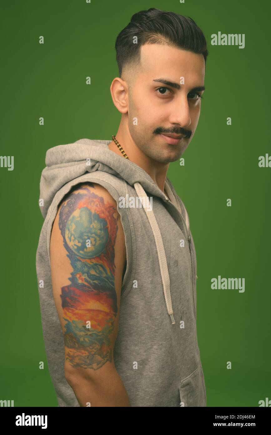 Young handsome Iranian man with mustache against green background Stock ...