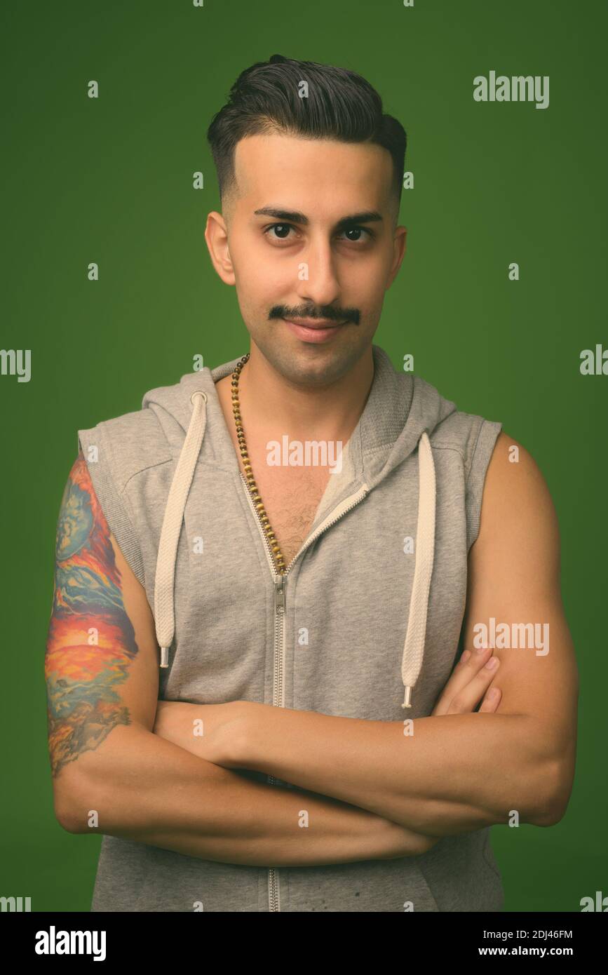 Young handsome Iranian man with mustache against green background Stock ...