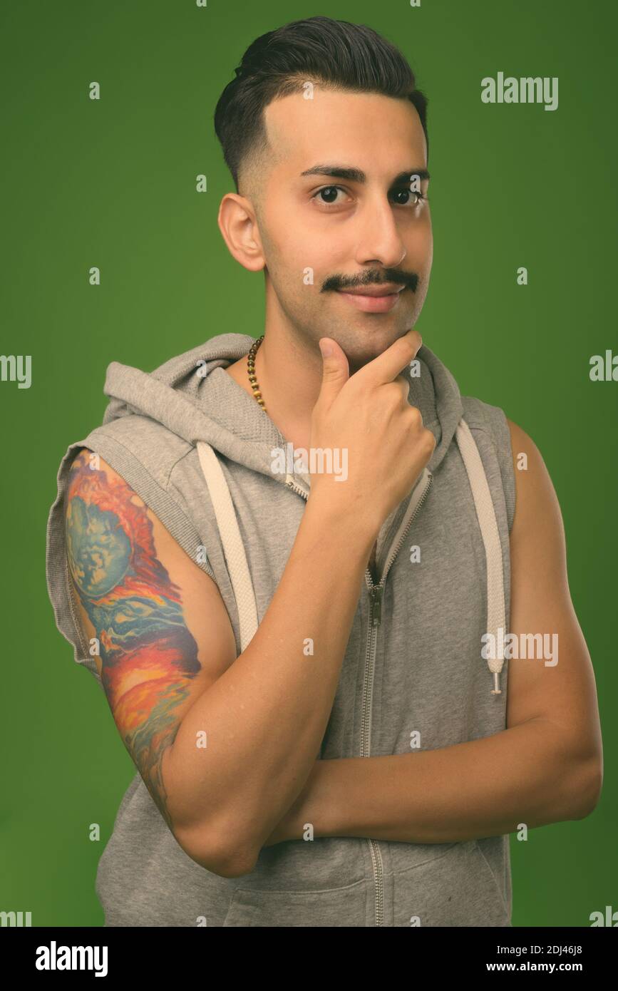 Young handsome Iranian man with mustache against green background Stock ...