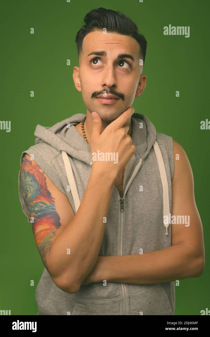 Young handsome Iranian man with mustache against green background Stock ...