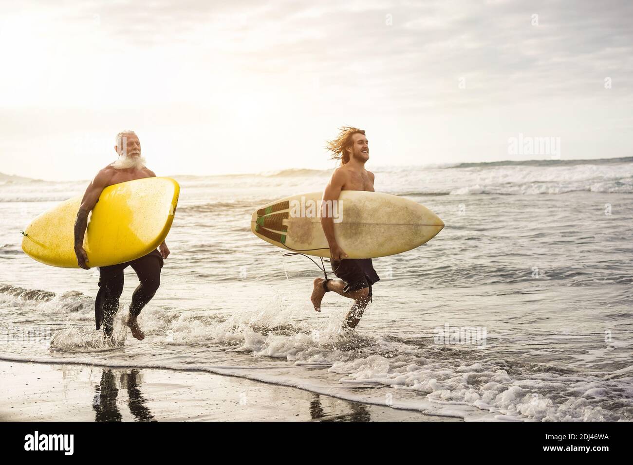 Father and son surfers run along the beach with longboards - Focus on ...