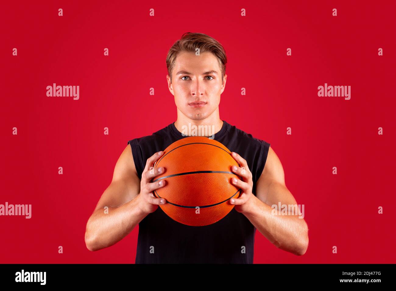 Portrait of determined young basketballer holding ball and looking at ...