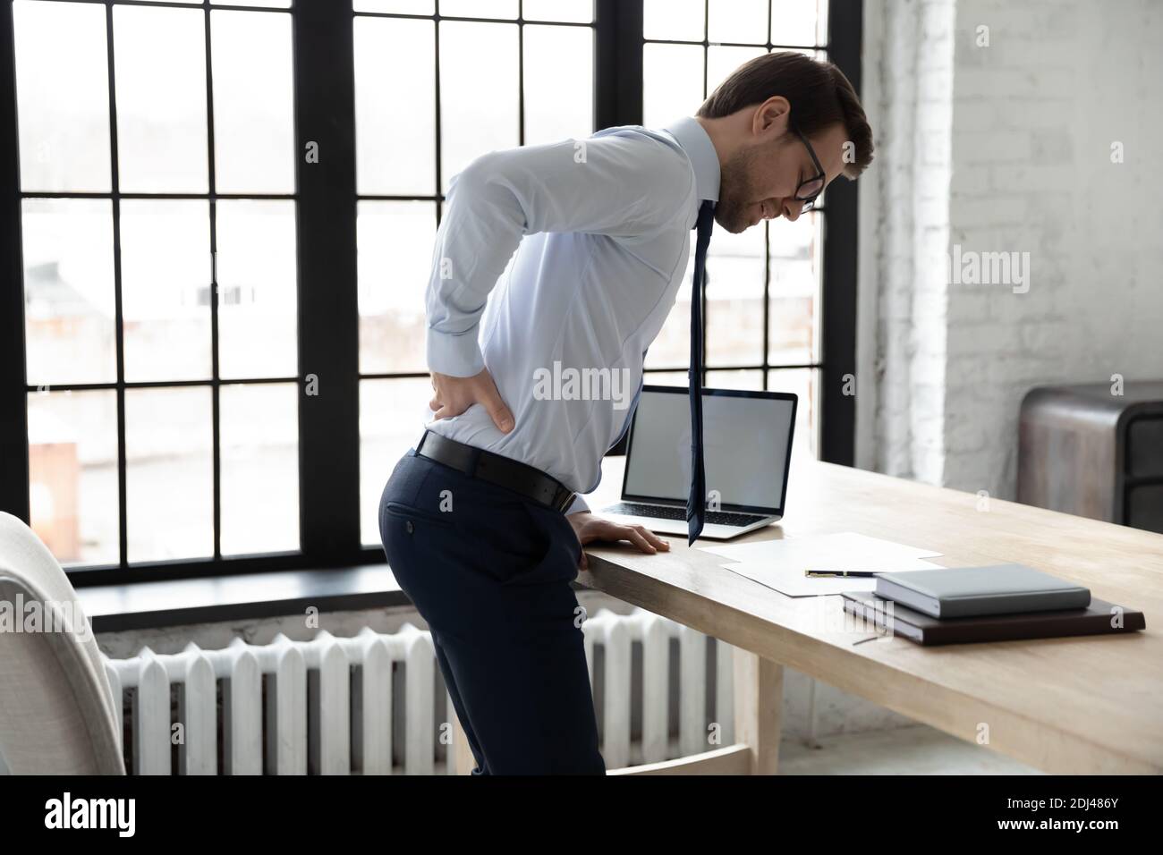 Unhealthy businessman touching lower back, suffering from backache in ...
