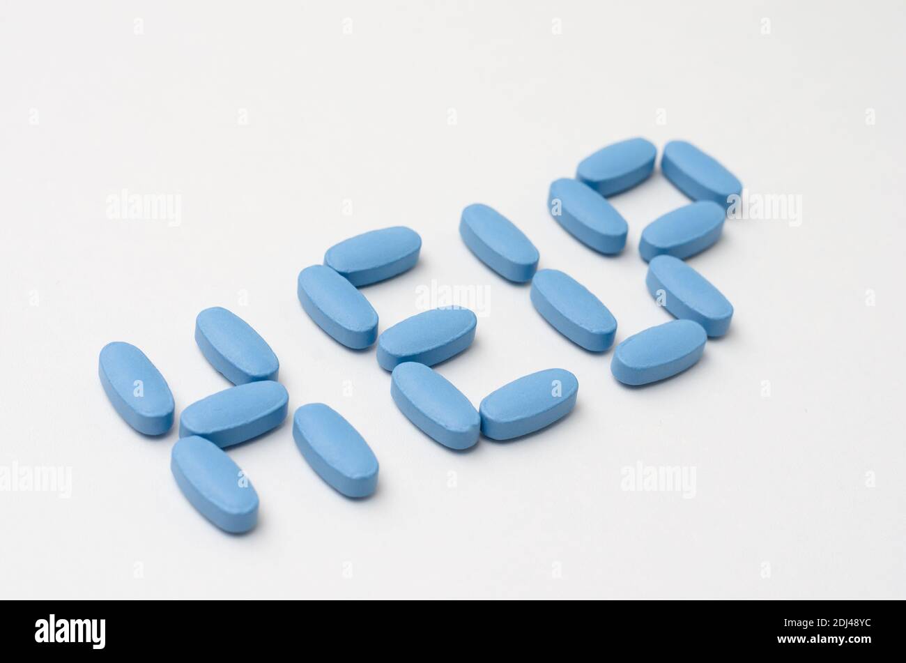 Close- up of HELP word written with blue pills on white background ...