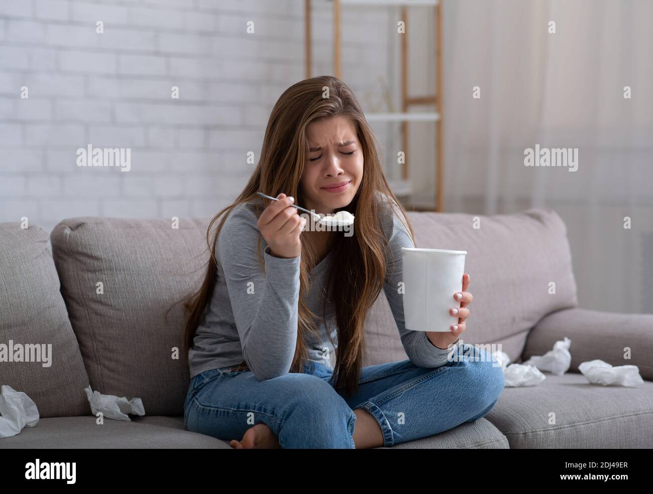 Sad millennial lady crying and eating ice cream while watching romantic ...