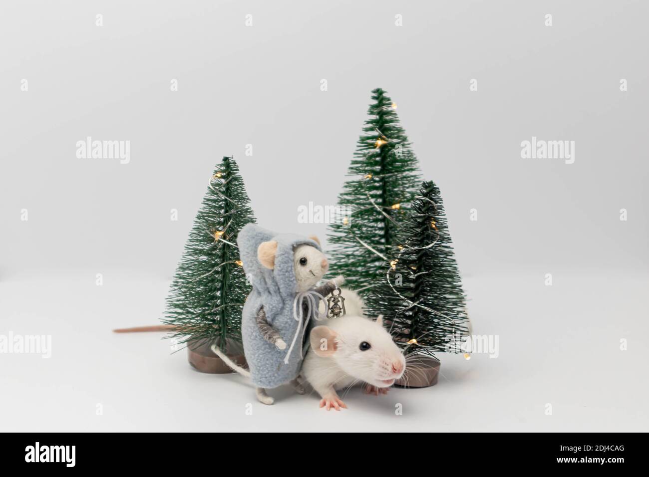 White little rat among beautiful holiday trees in the forest. A toy in ...