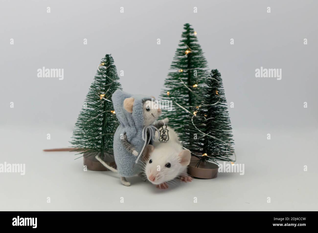 White little rat among beautiful holiday trees in the forest. A toy in ...