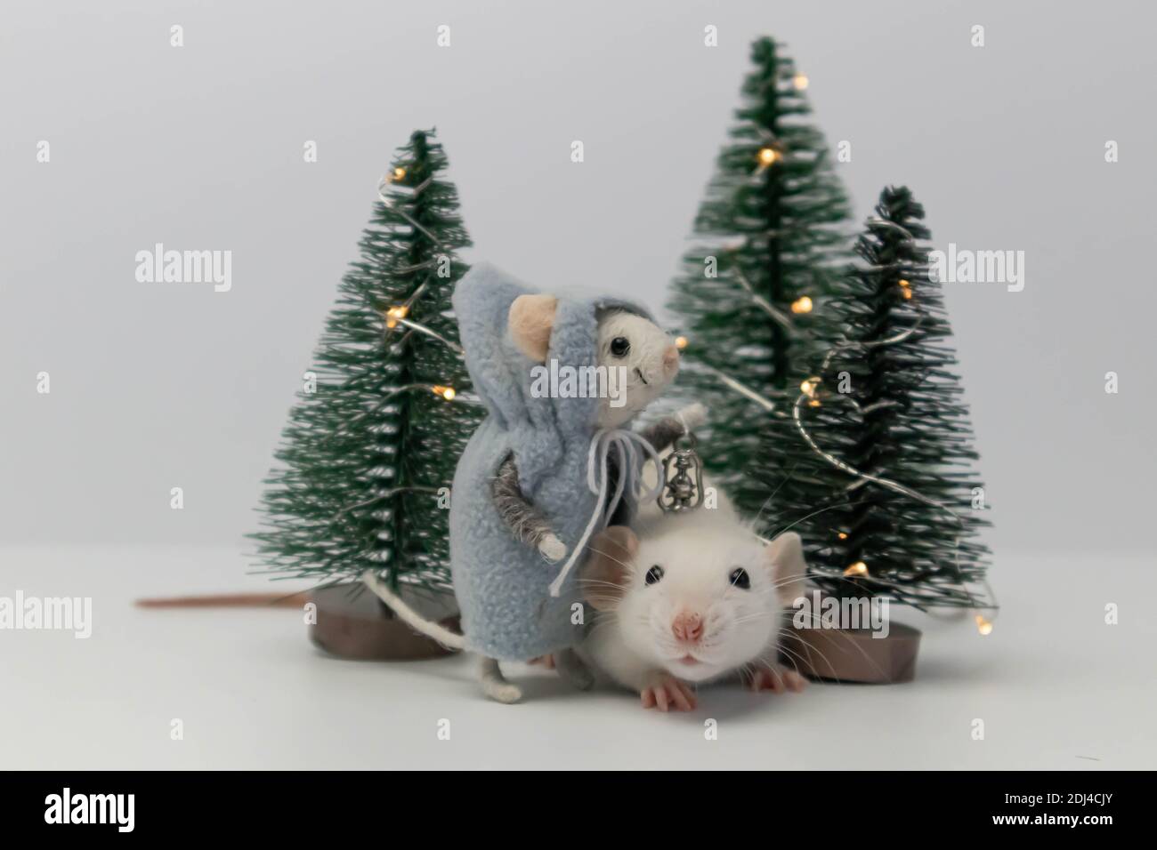 White little rat among beautiful holiday trees in the forest. A toy in ...