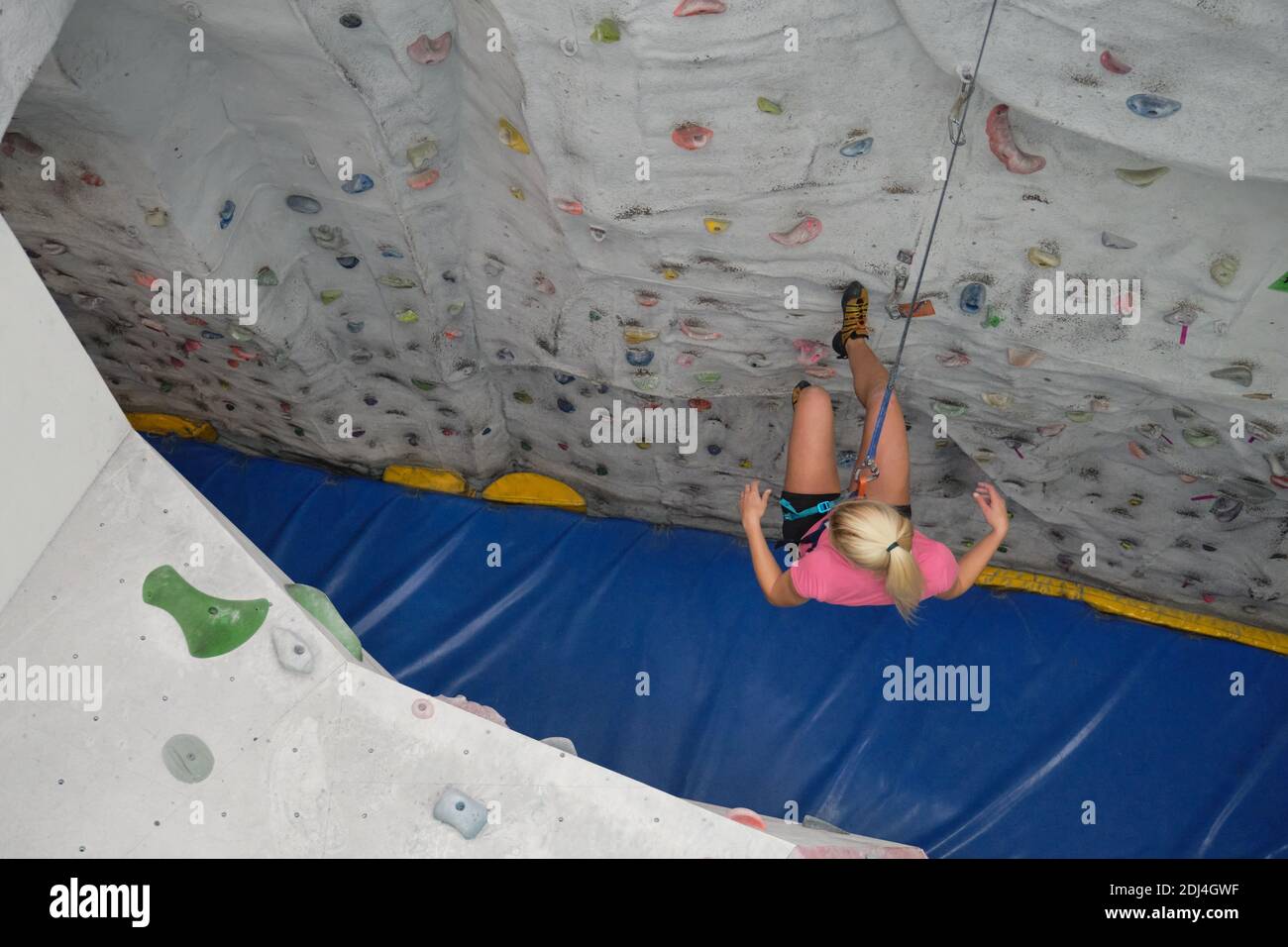 Top view of a young caucasian blonde woman rappelling at indoor ...