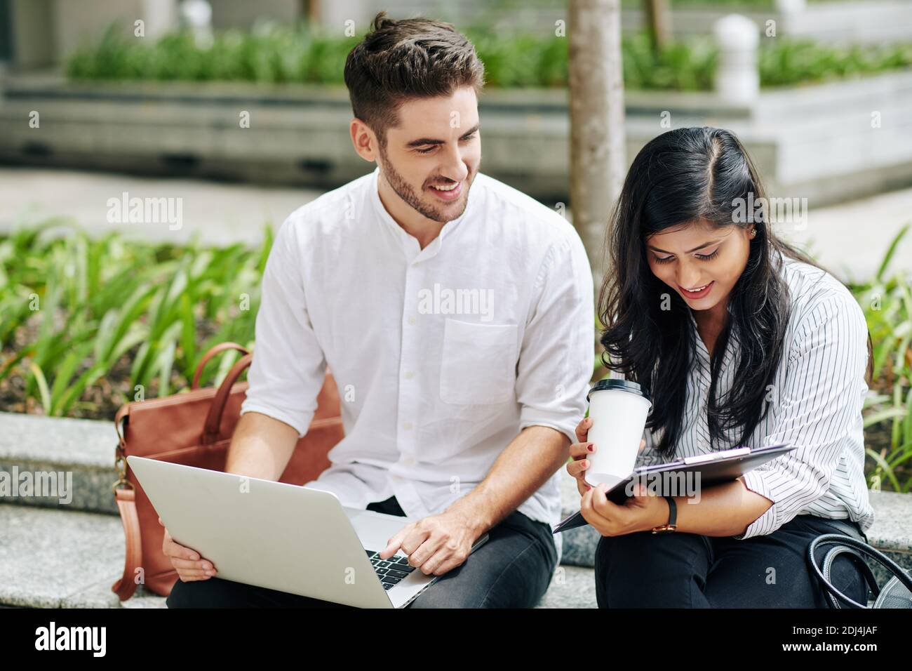 Smiling colleagues discussing report Stock Photo - Alamy