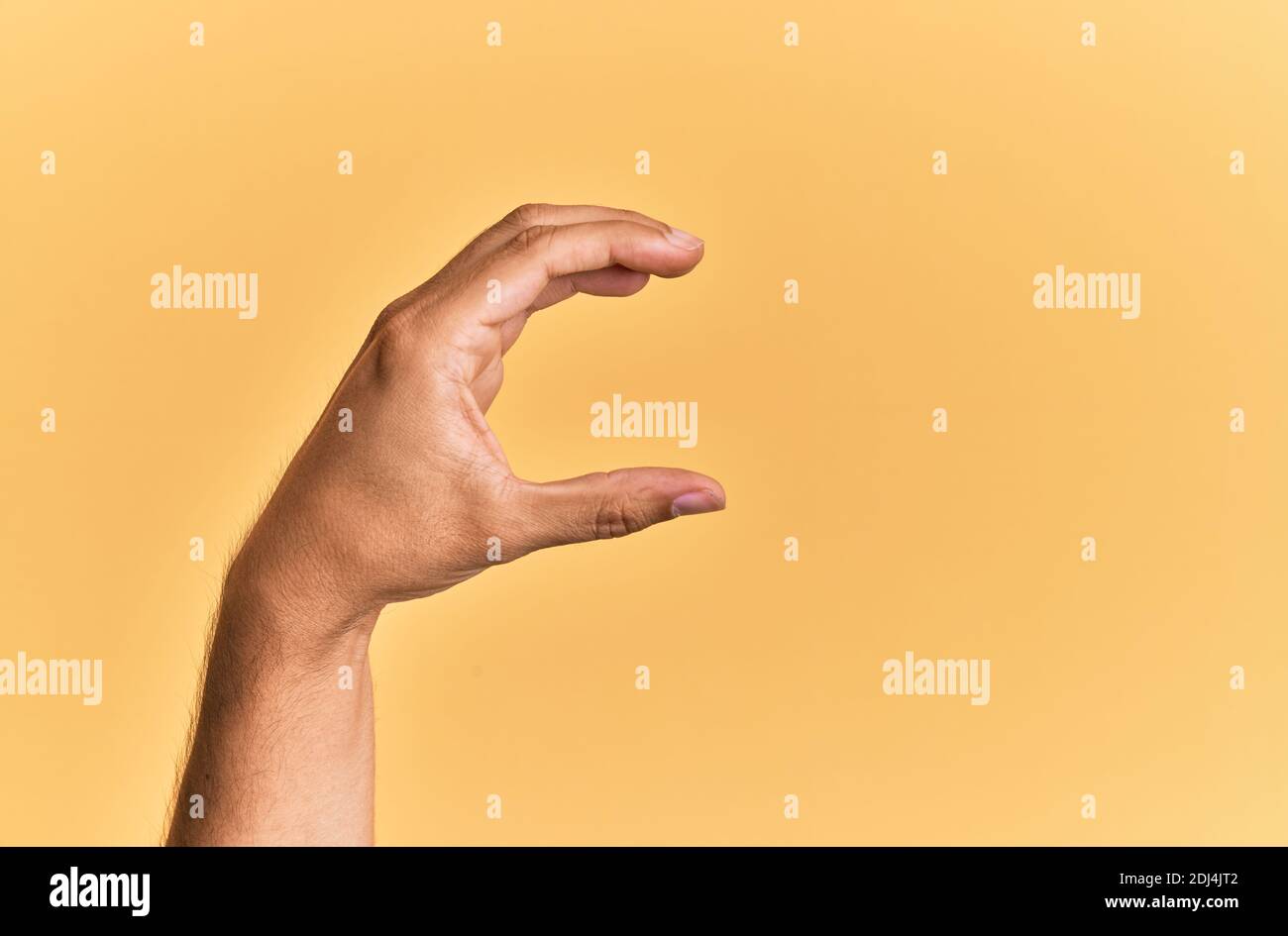 Arm and hand of caucasian man over yellow isolated background picking ...
