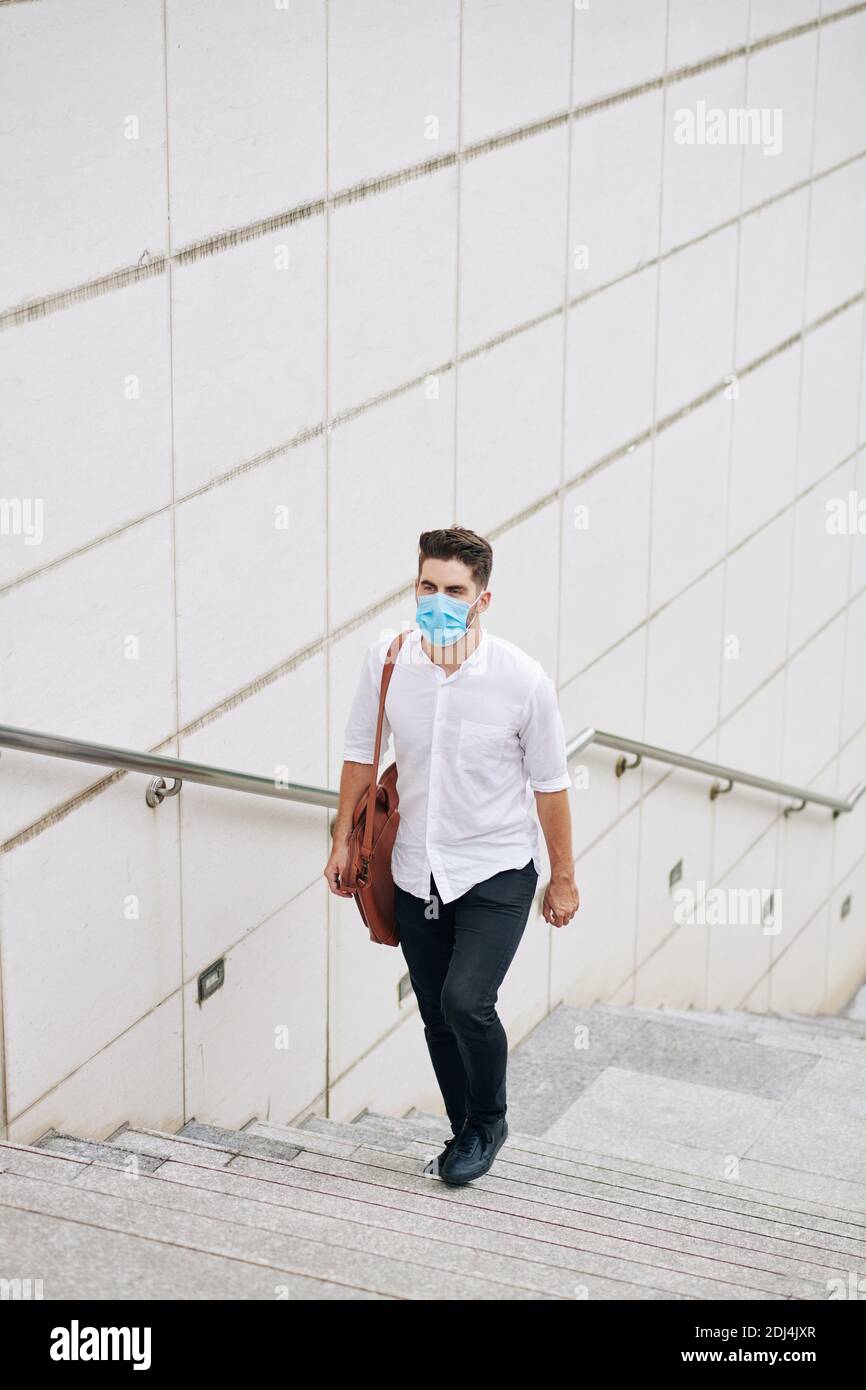 Man in mask walking up the stairs Stock Photo - Alamy