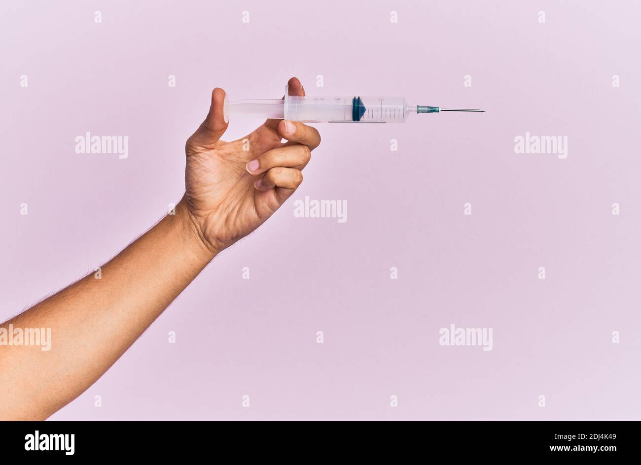 Hand of young hispanic man holding syringe over isolated pink background Stock Photo - Alamy