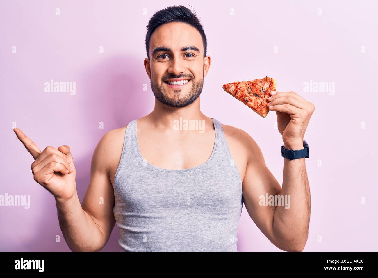 Young handsome man with beard eating slice of Italian pizza over ...
