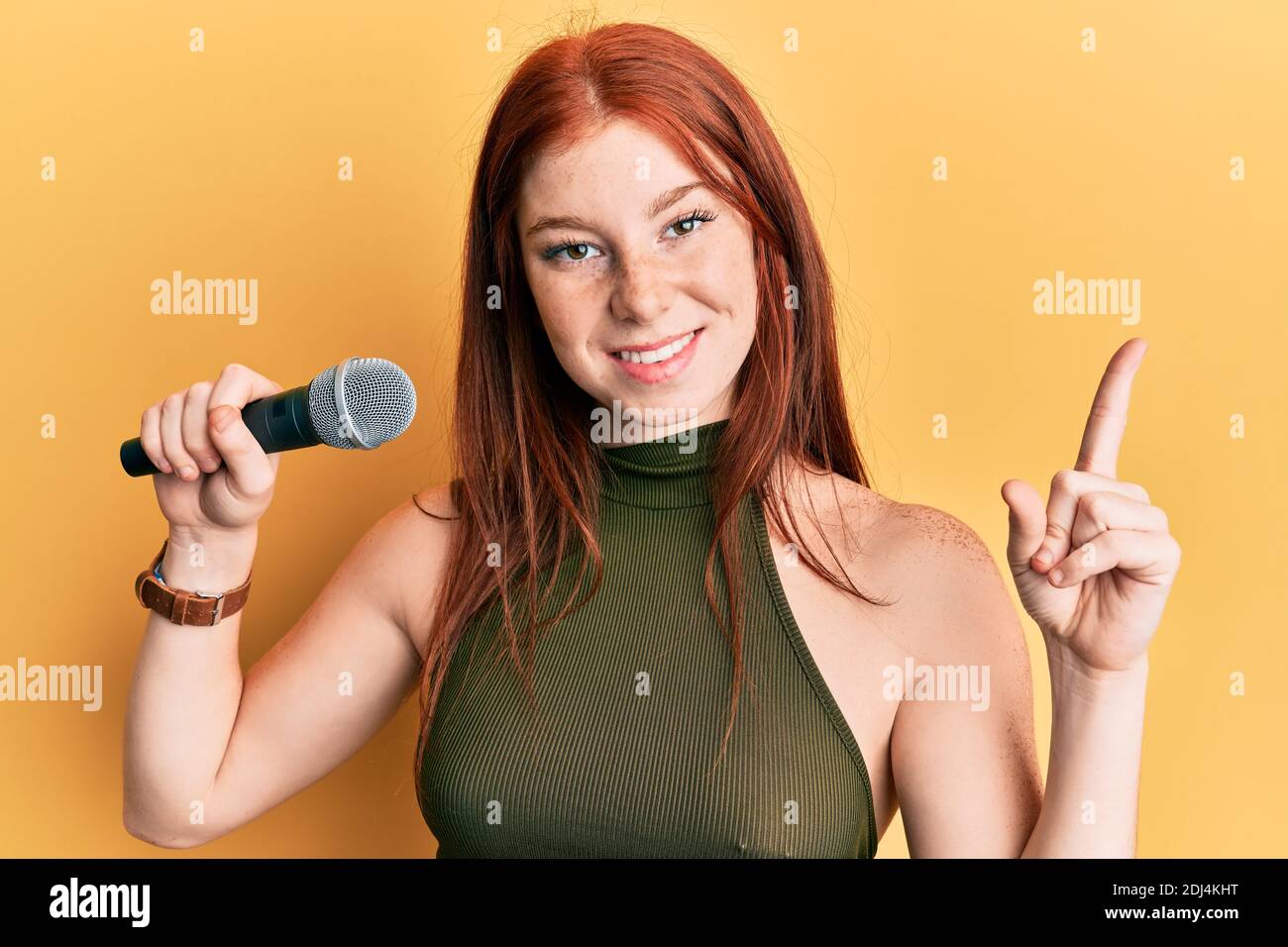 Young red head girl singing song using microphone smiling happy ...