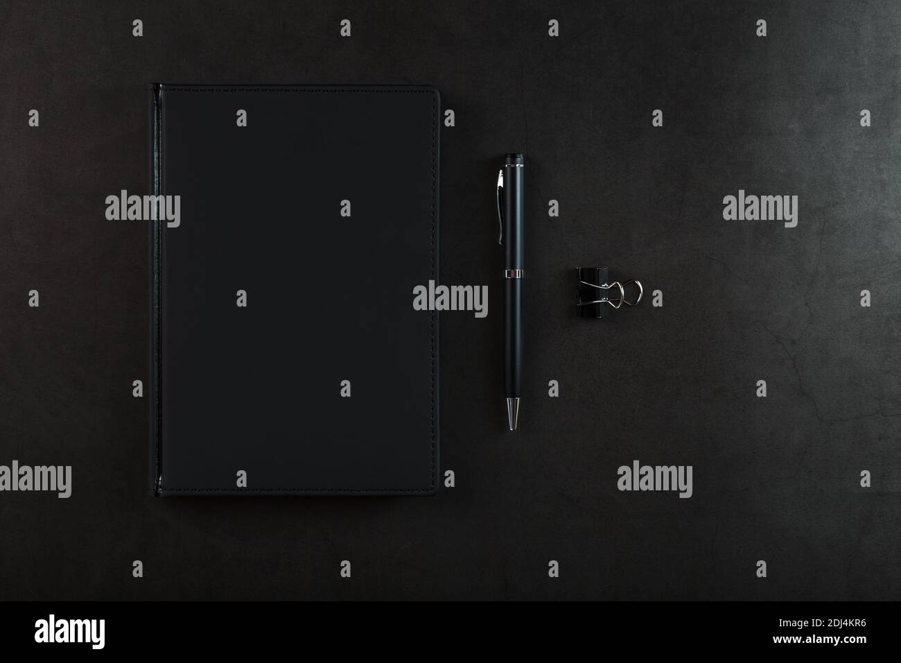 Black Notepad with a black pen on a black background. Top view ...