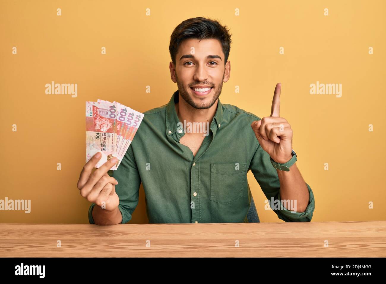 Young handsome man holding hong kong dollars banknotes smiling with an ...