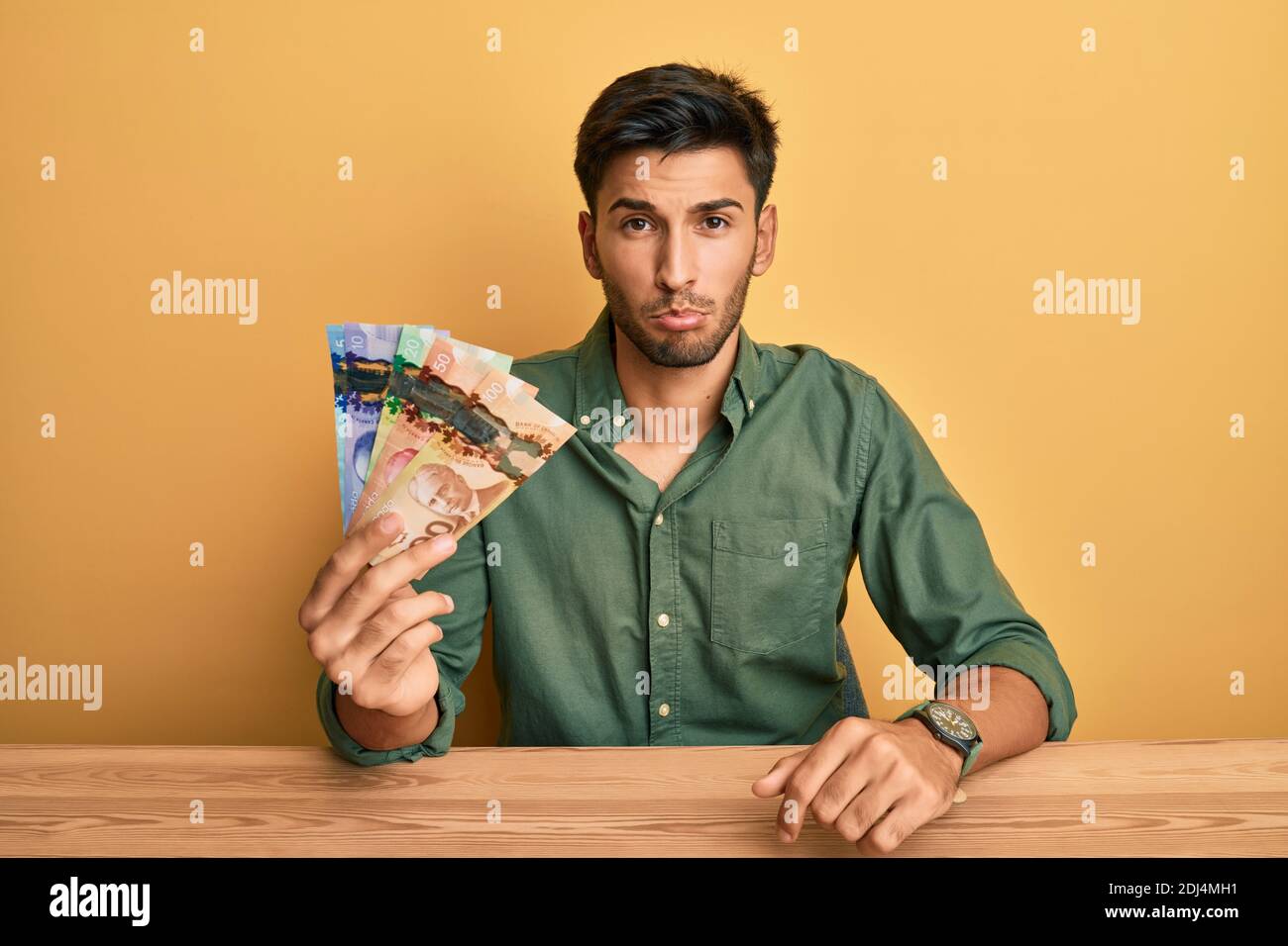 Young handsome man holding canadian dollars depressed and worry for ...