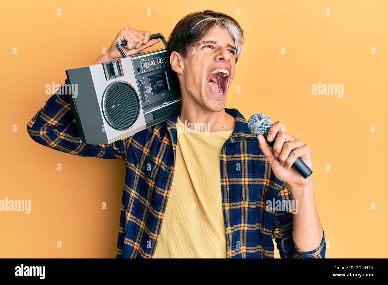 Young hispanic man singing song using microphone and boombox angry and ...