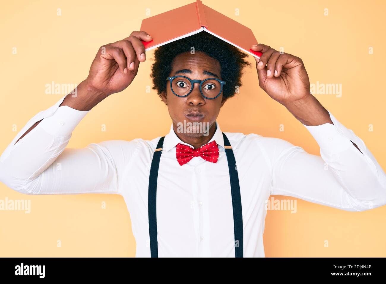 Handsome african american nerd man with afro hair holding book over ...