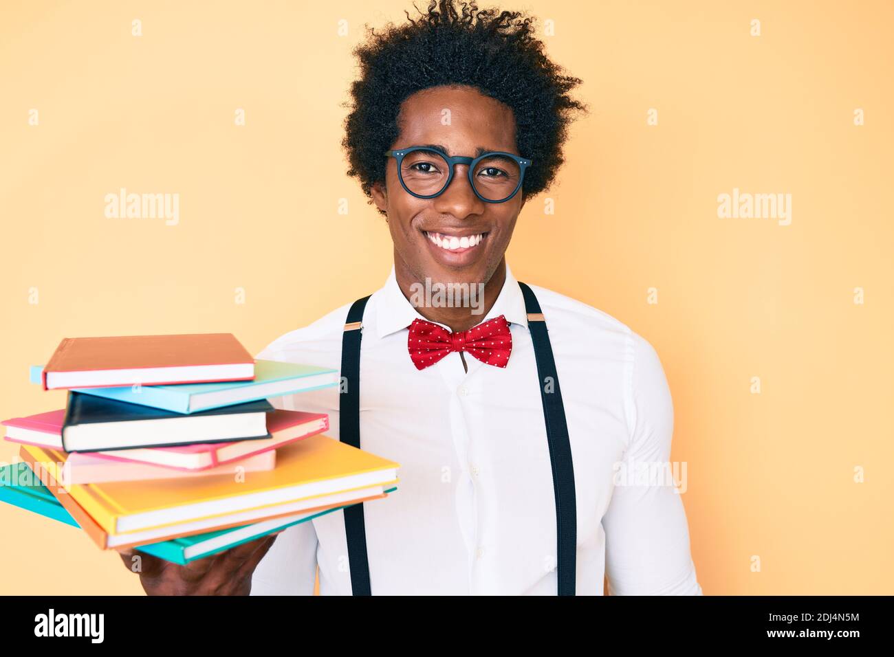 Handsome african american nerd man with afro hair holding books looking ...