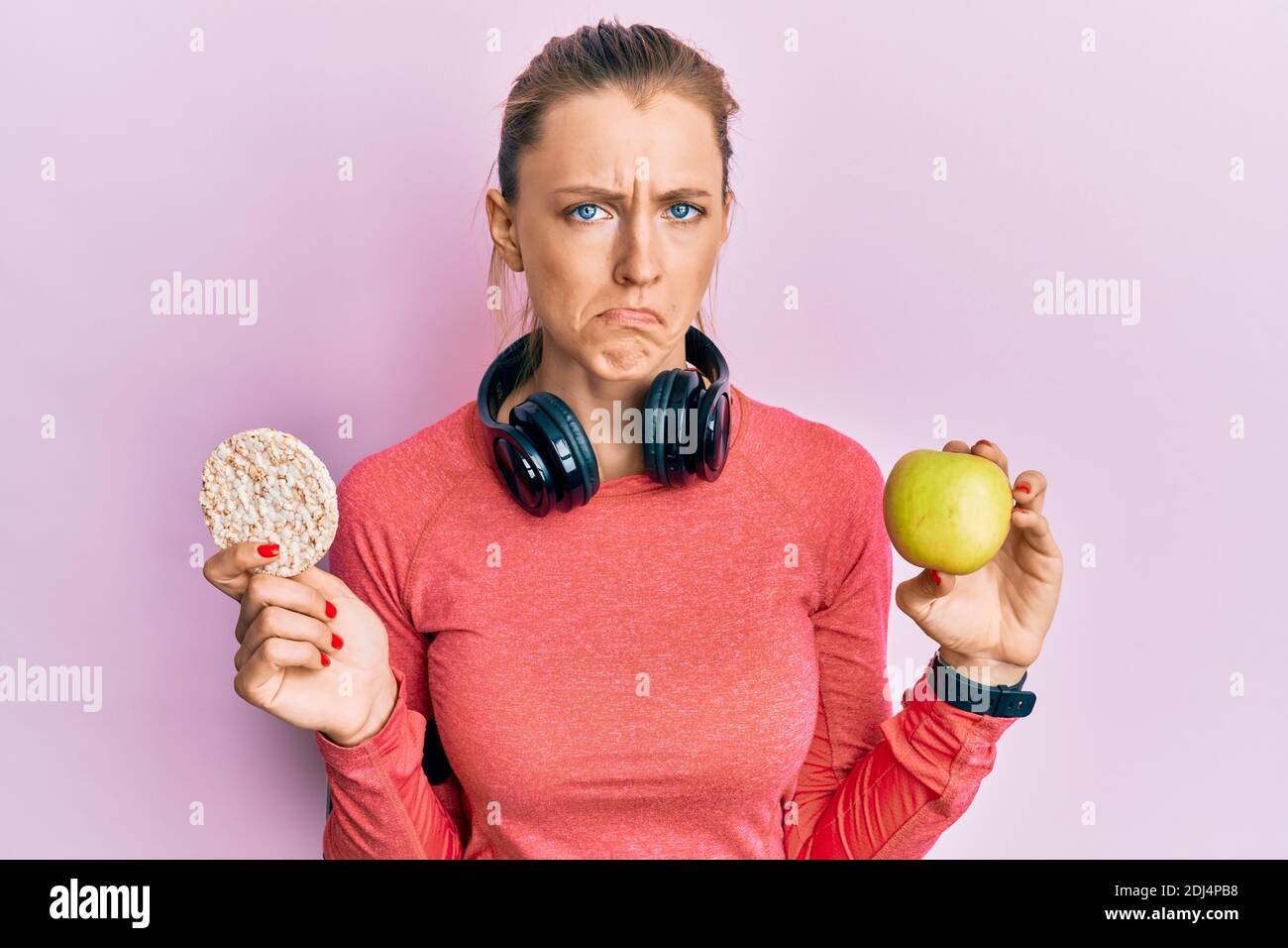Beautiful caucasian sports woman holding green apple and rice crackers ...