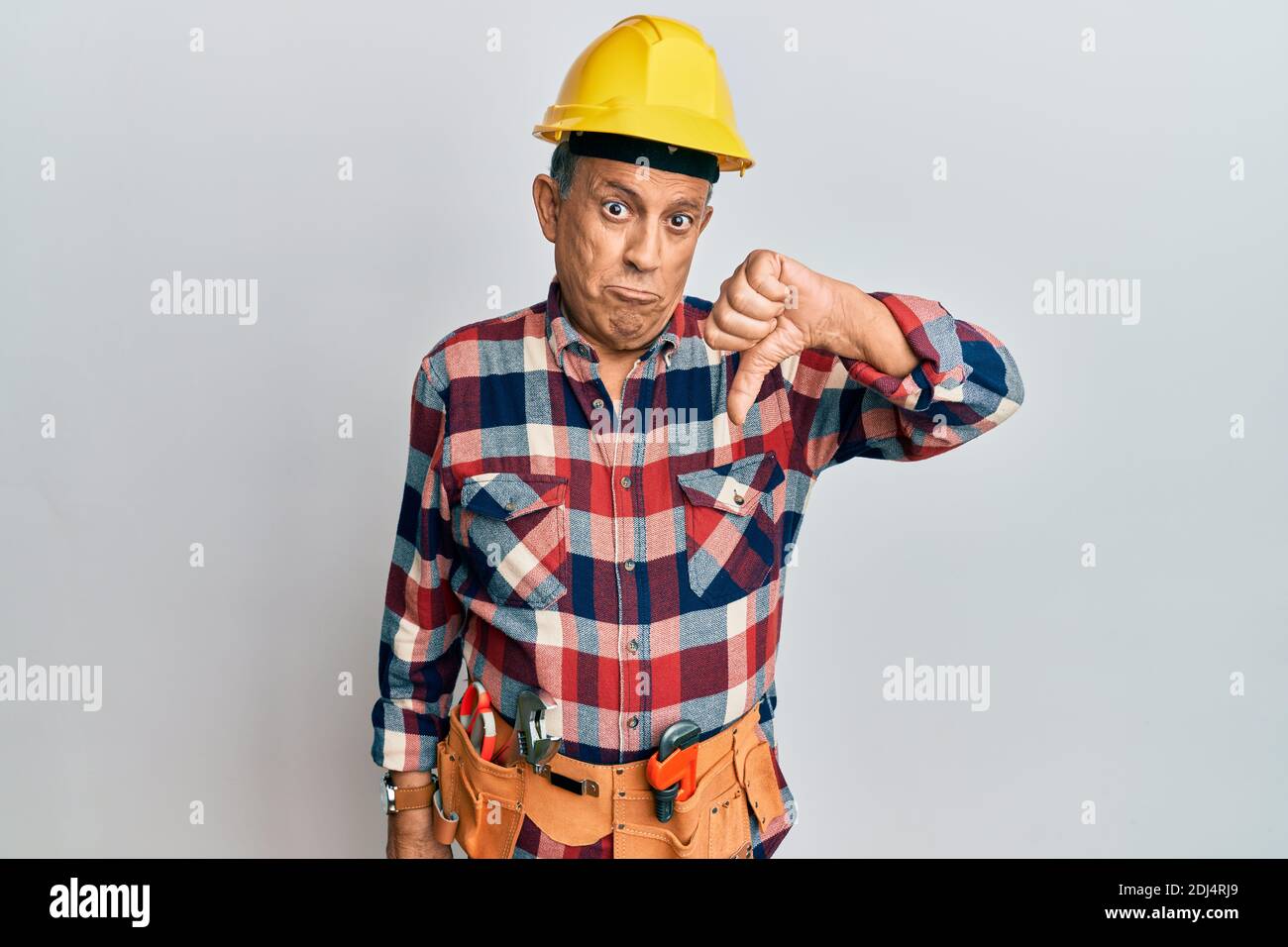 Senior hispanic man wearing handyman uniform looking unhappy and angry ...