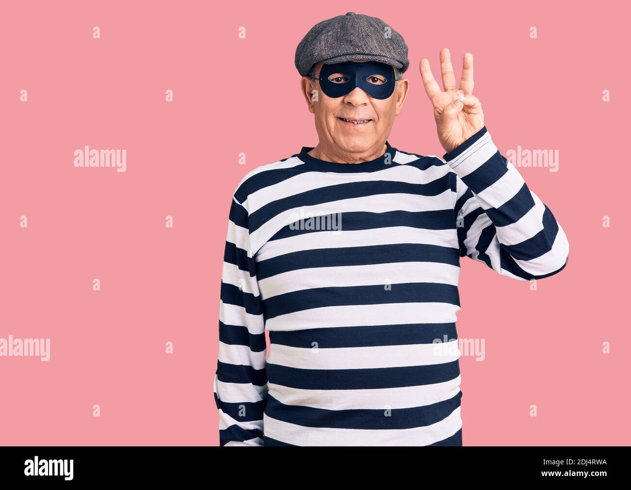 Senior handsome man wearing burglar mask and t-shirt showing and ...