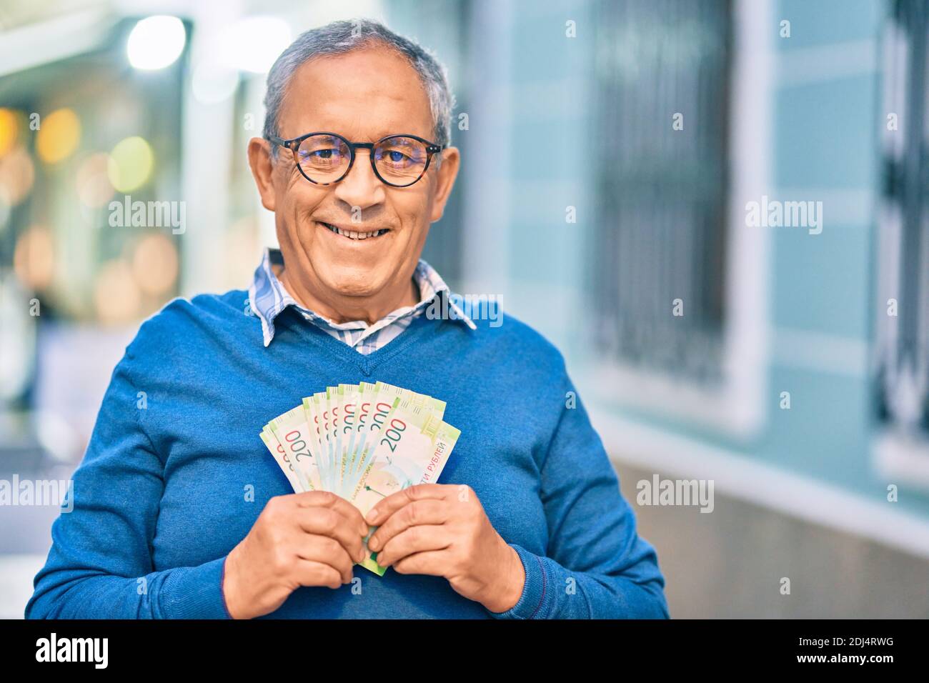 Senior grey-haired man smiling happy holding russian ruble banknotes at ...