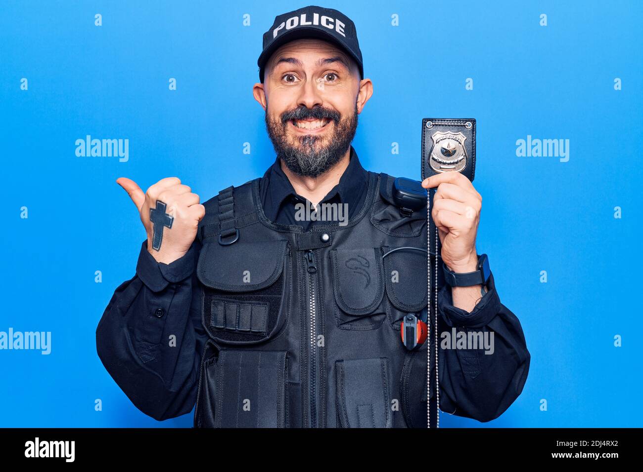 Young handsome man wearing police uniform holding gun pointing thumb up ...