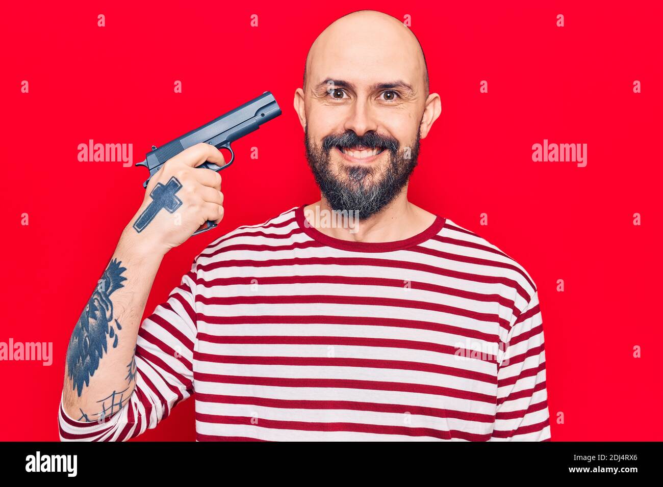 Young handsome man holding gun looking positive and happy standing and ...