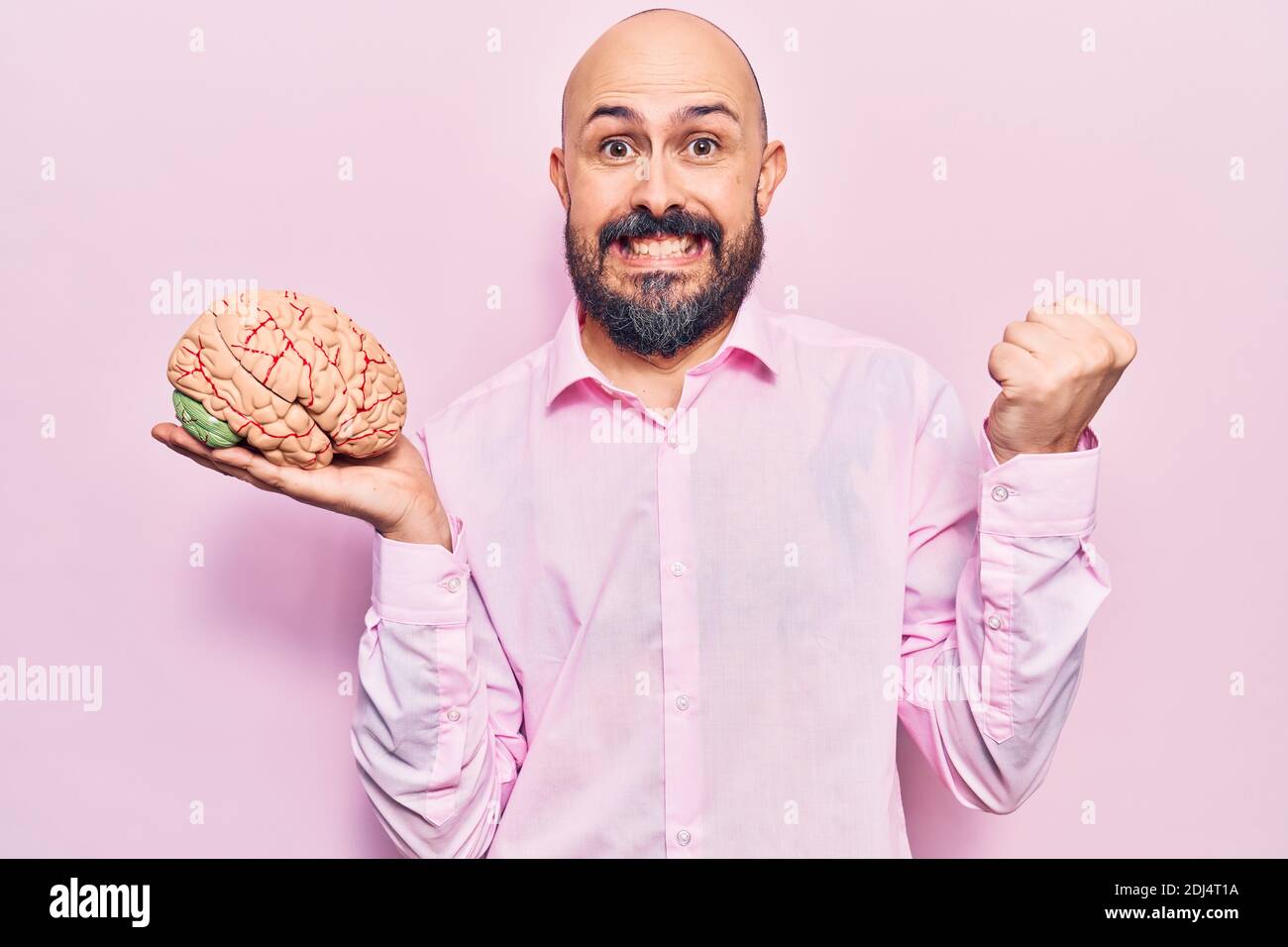 Young handsome man holding brain screaming proud, celebrating victory ...