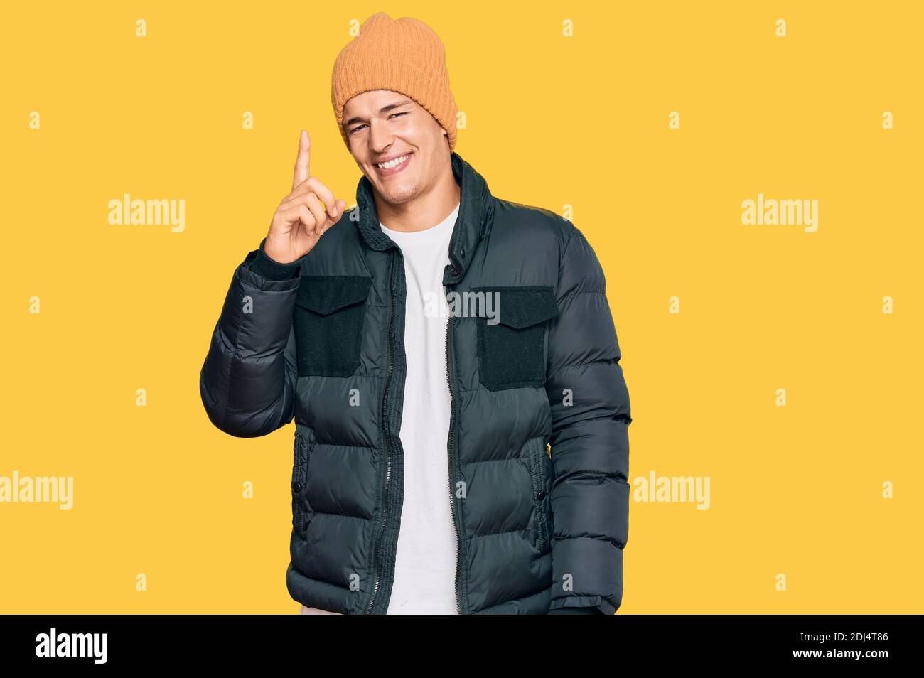 Handsome caucasian man wearing snow wear pointing finger up with ...