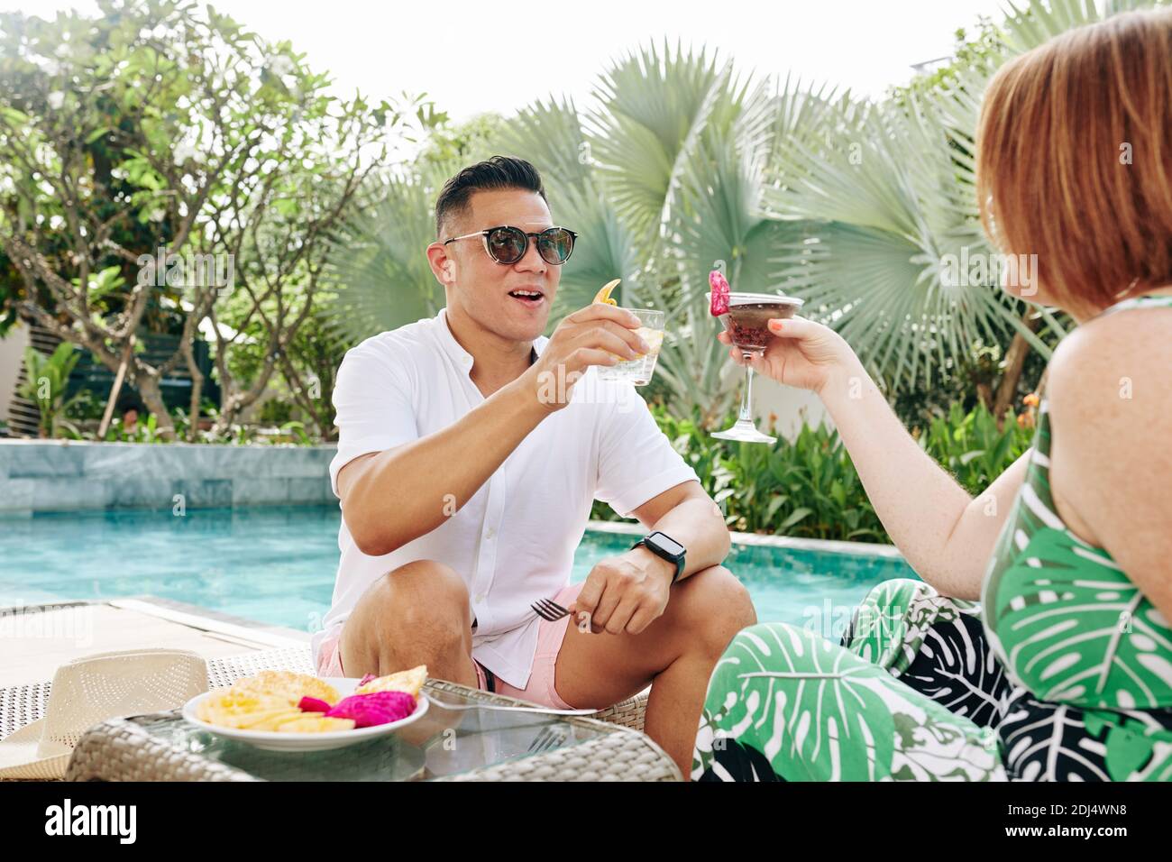 Cheerful couple toasting with sweet refreshing cocktails when spending ...