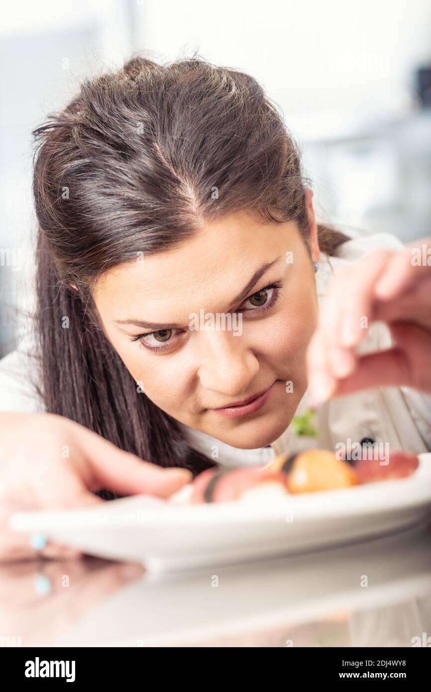 Good looking female chef gives the dish a finishing touch Stock Photo ...