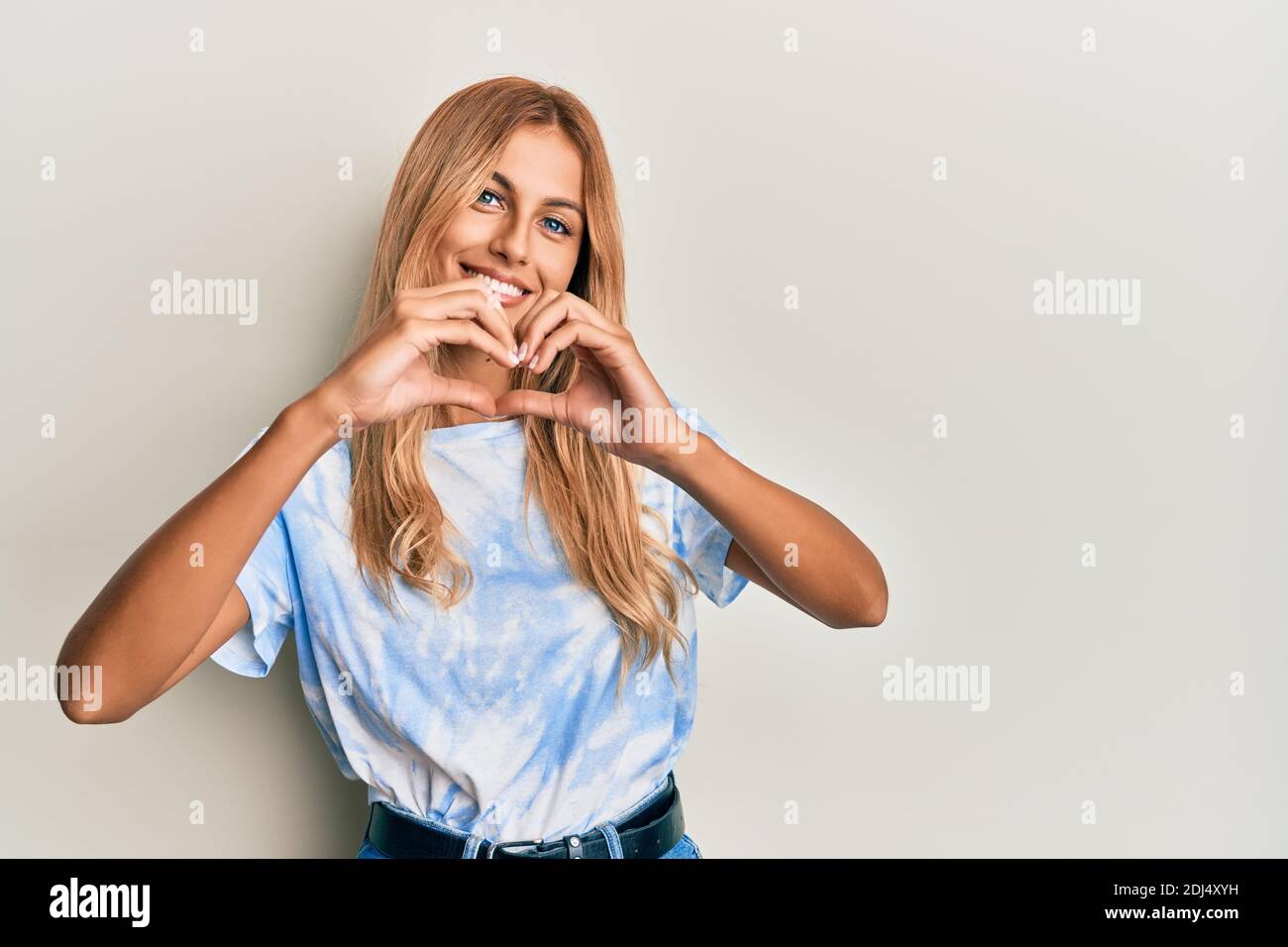 Beautiful blonde young woman wearing tye die tshirt smiling in love ...
