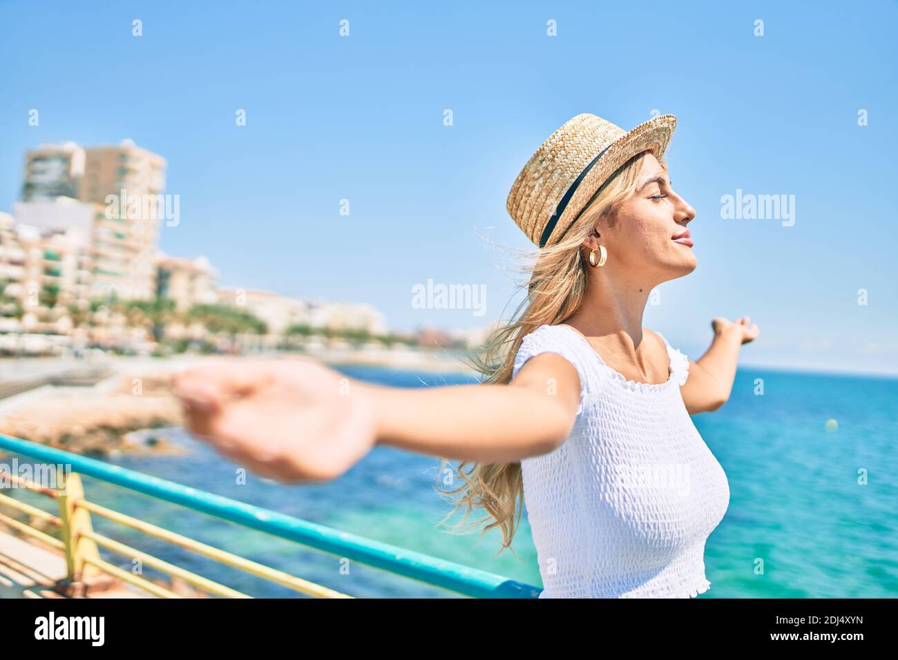 Young blonde tourist girl breathing with close eyes and open arms at ...