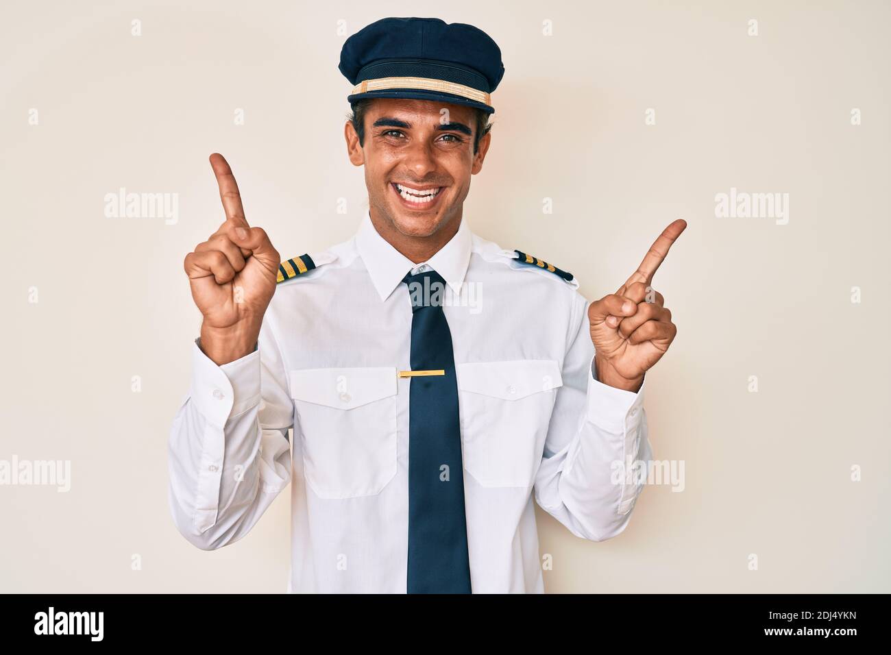 Young hispanic man wearing airplane pilot uniform smiling confident ...